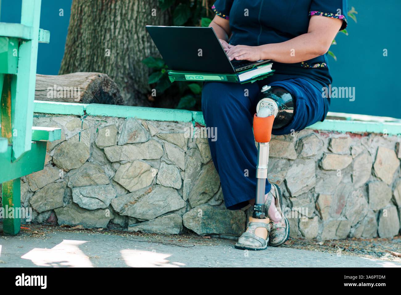 View of a Latina woman's prosthetic leg working on her computer in a ...