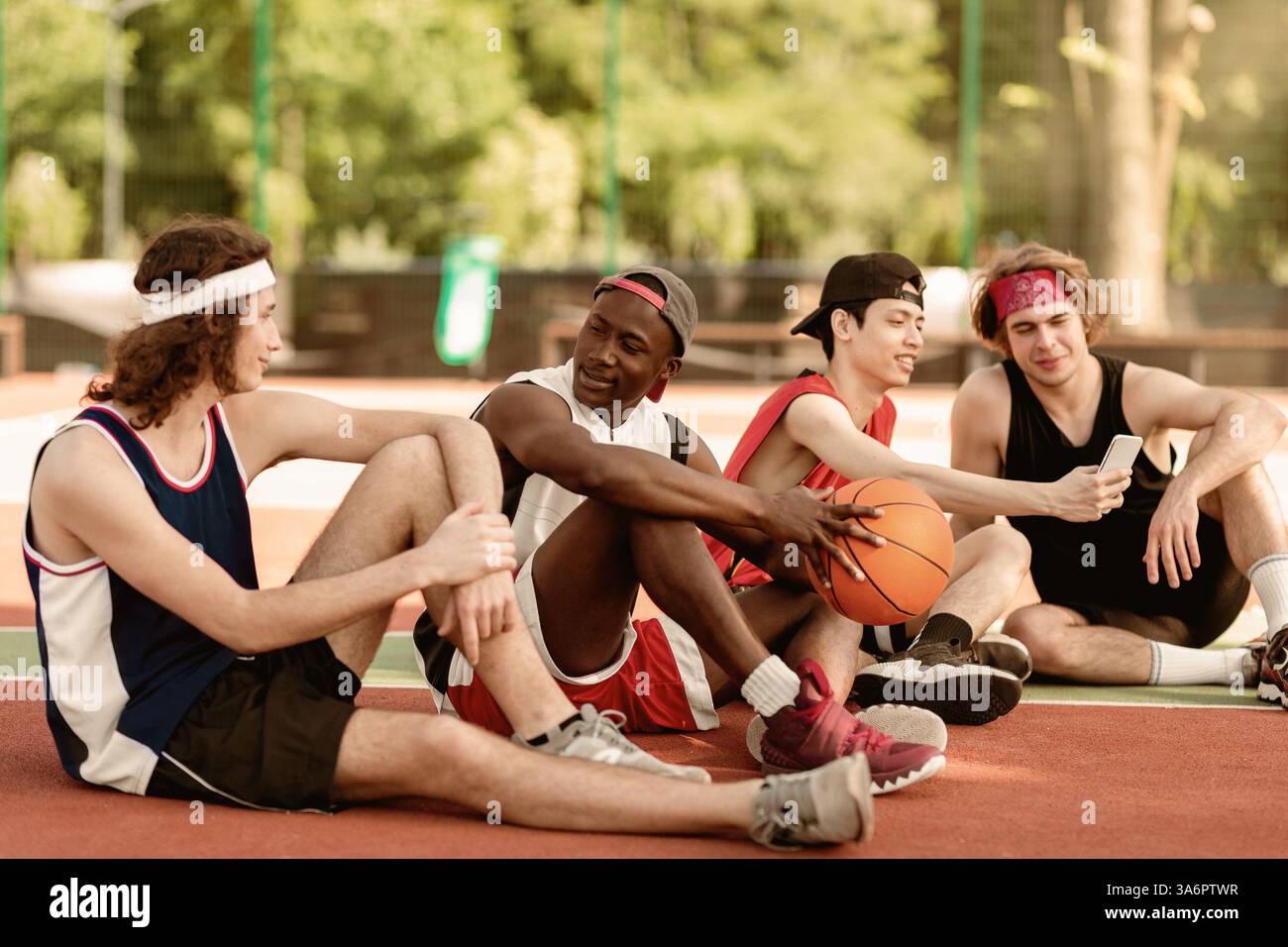 Group of basketball players resting after match at outdoor arena ...
