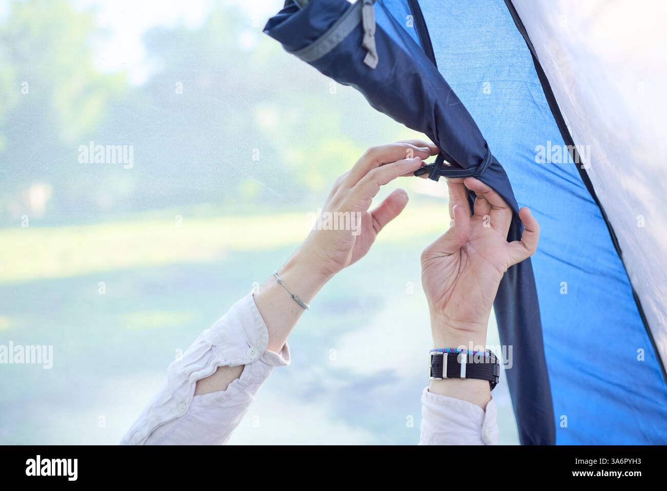 Hands of an unrecognizable person rolling up the door of his tent and ...