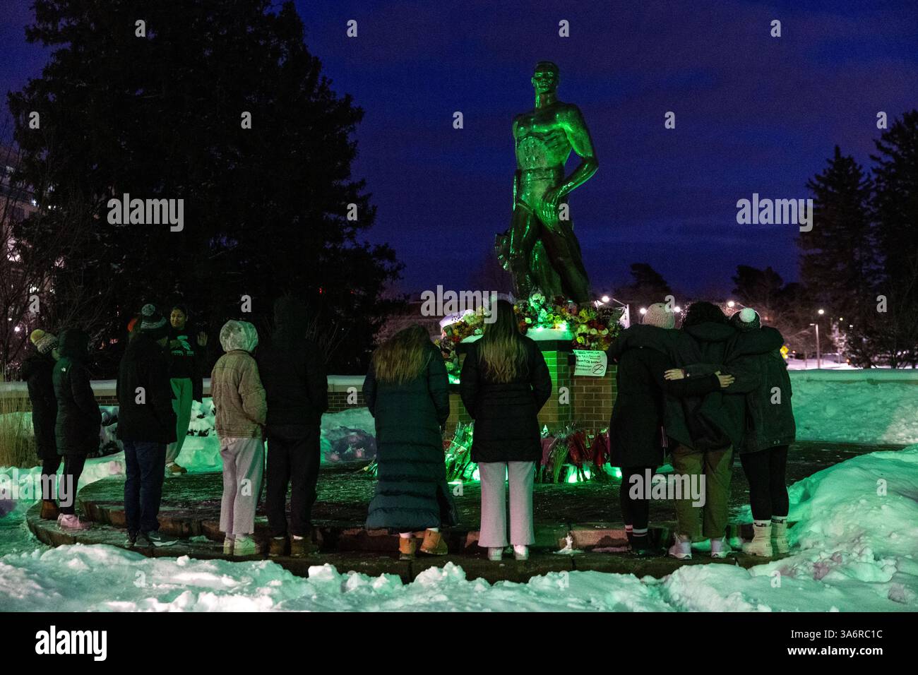 East Lansing, USA. 13th Feb, 2025. Community members leave flowers and ...