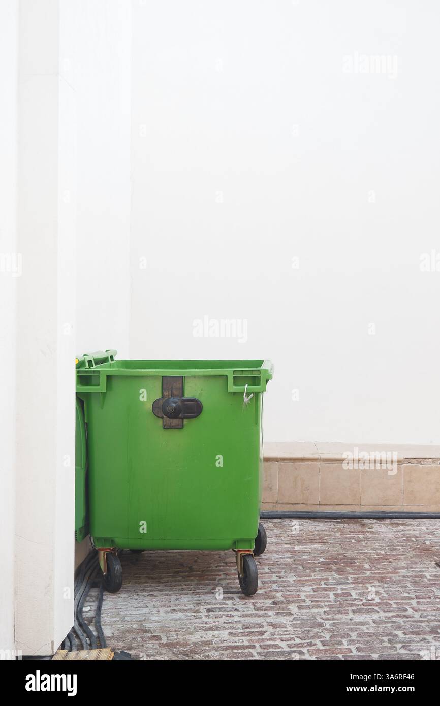 Green trash bin positioned in a corner of a clean outdoor area Stock ...