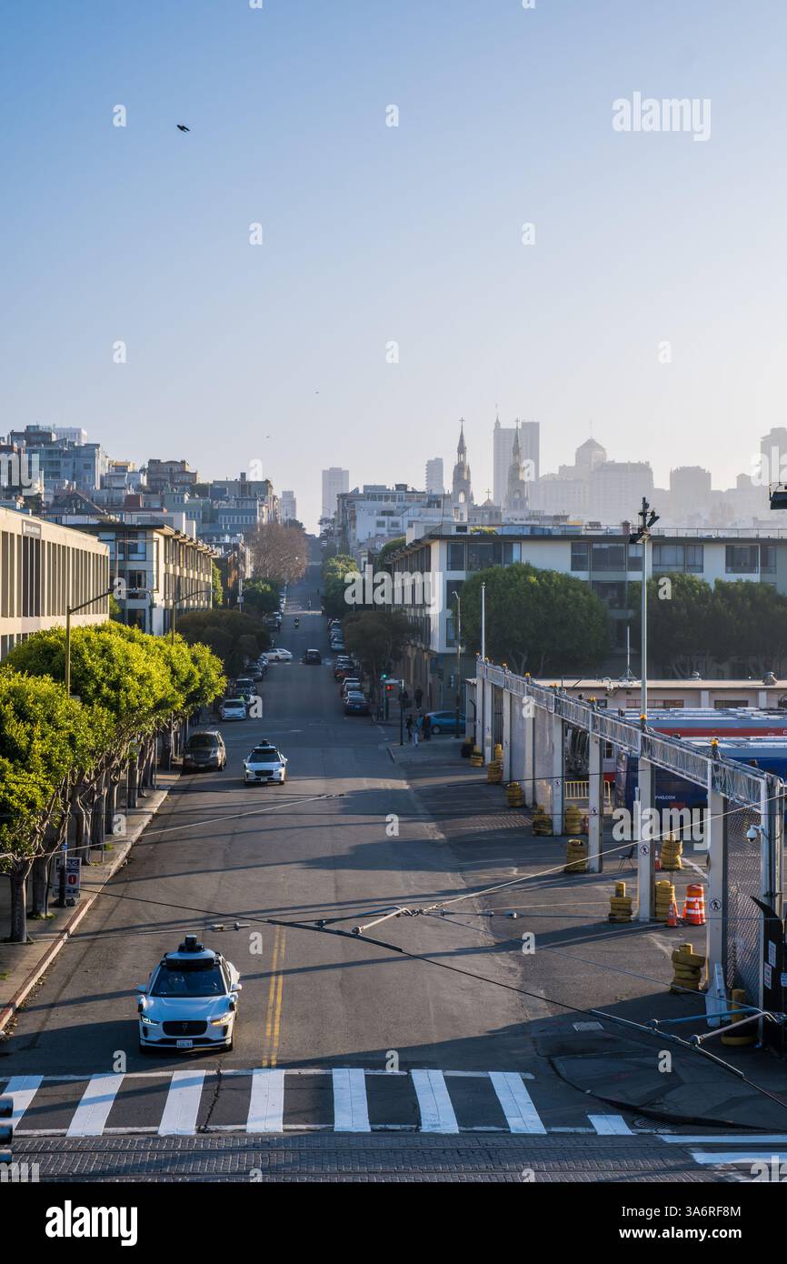 Cars line a quiet street under the soft morning light with buildings ...