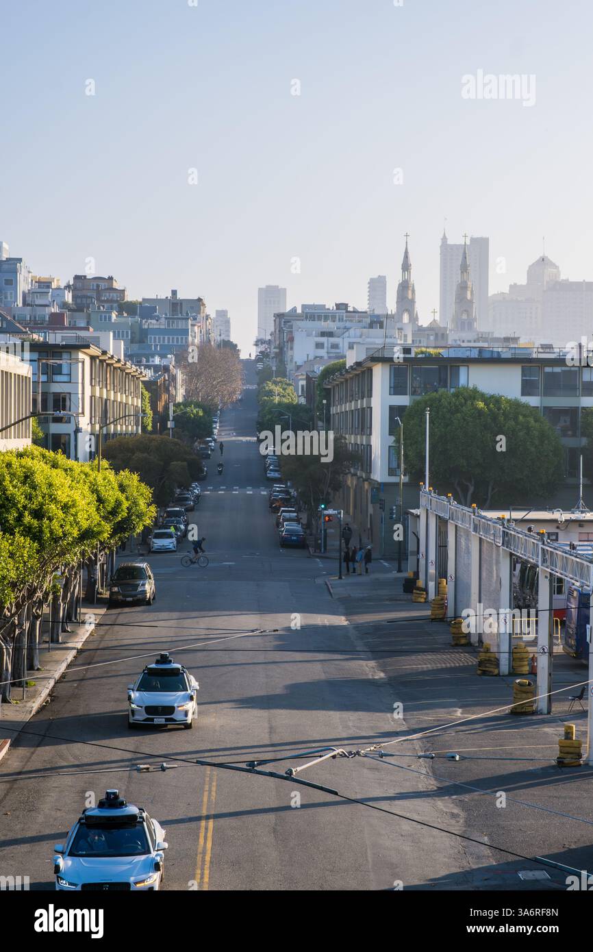 Self-driving cars navigate a lively street lined with trees and ...