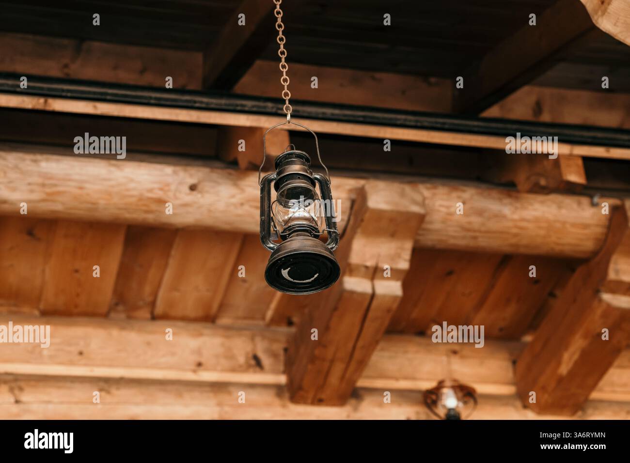 Traditional kerosene lamp hanging on wooden construction of a log cabin ...