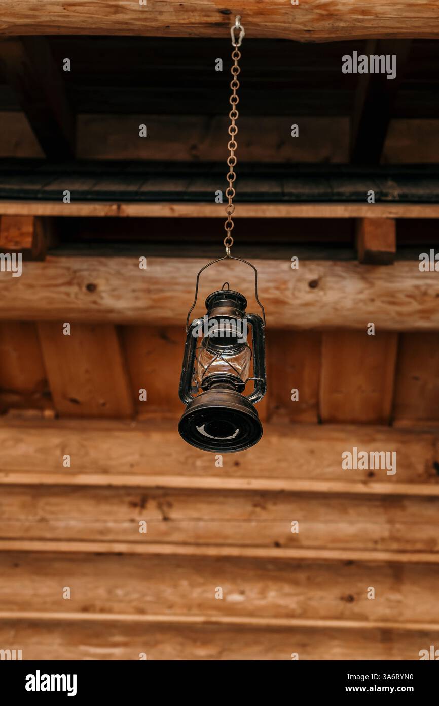 Traditional kerosene lamp hanging on wooden construction of a log cabin ...