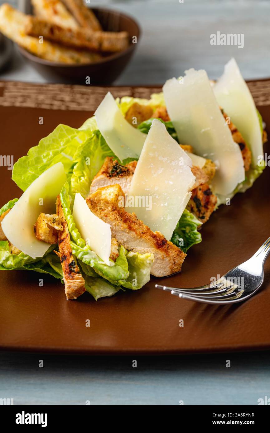 Chicken Caesar salad served on a porcelain plate with crusty bread ...