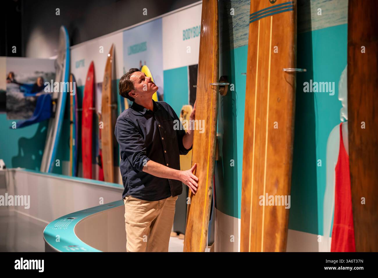 Champion longboarder and exhibition curator Dr Sam Bleakley inspects a ...