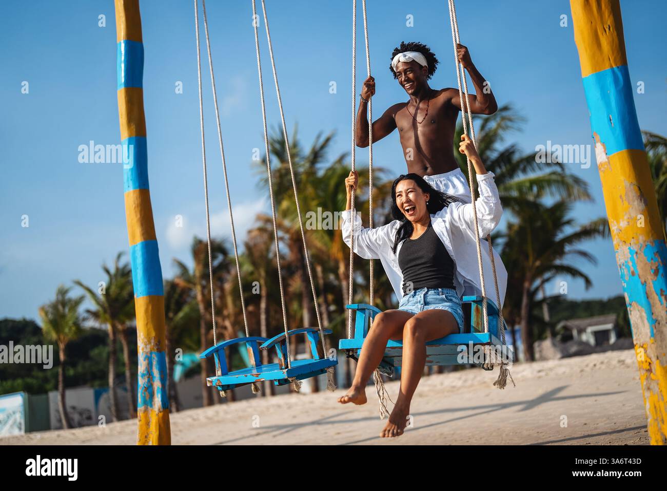 Interracial couple enjoying the freedom of summer, laughing and playing on a tropical beach ...