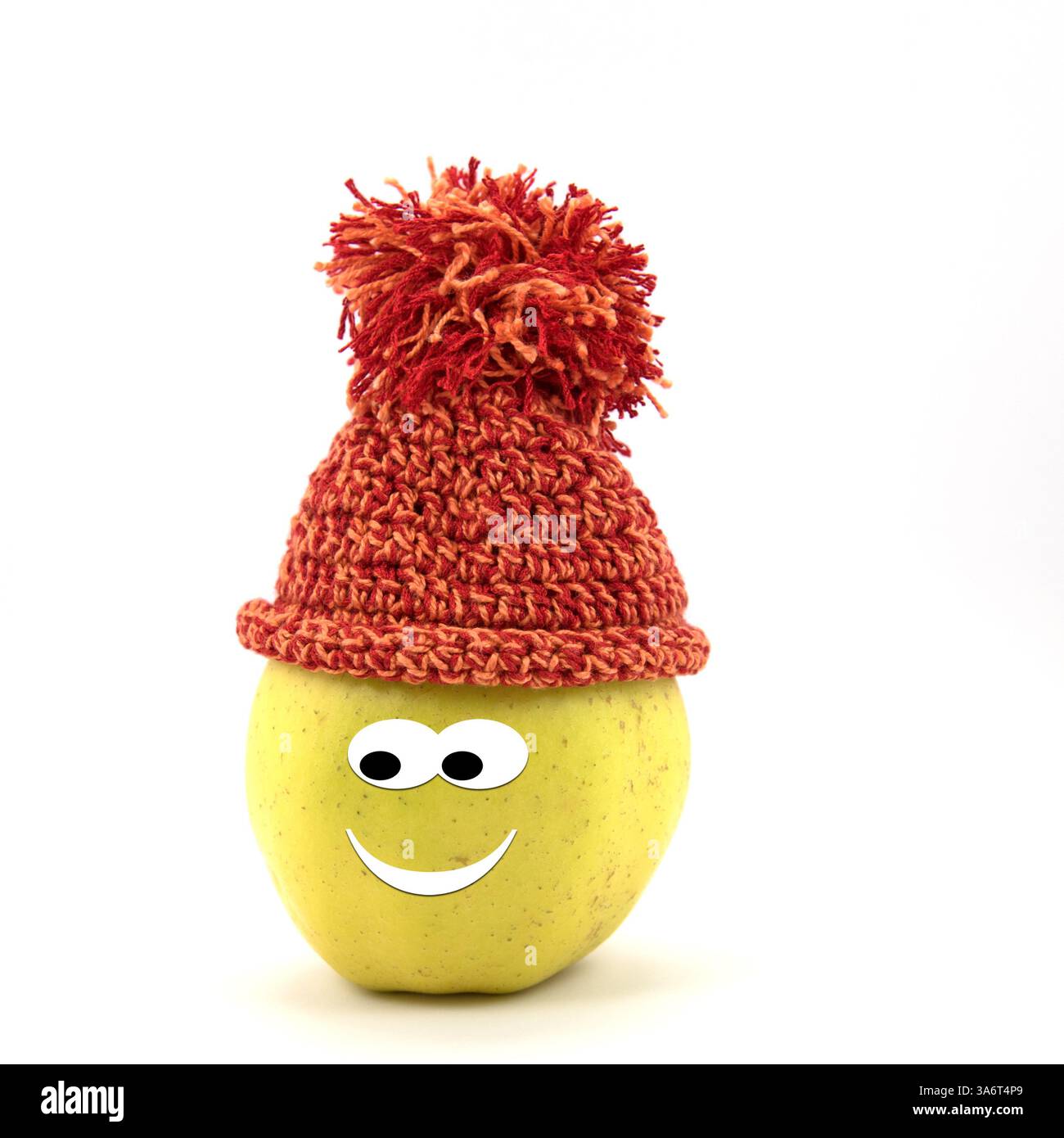 Apple with face and bobble hat against a white background Stock Photo ...