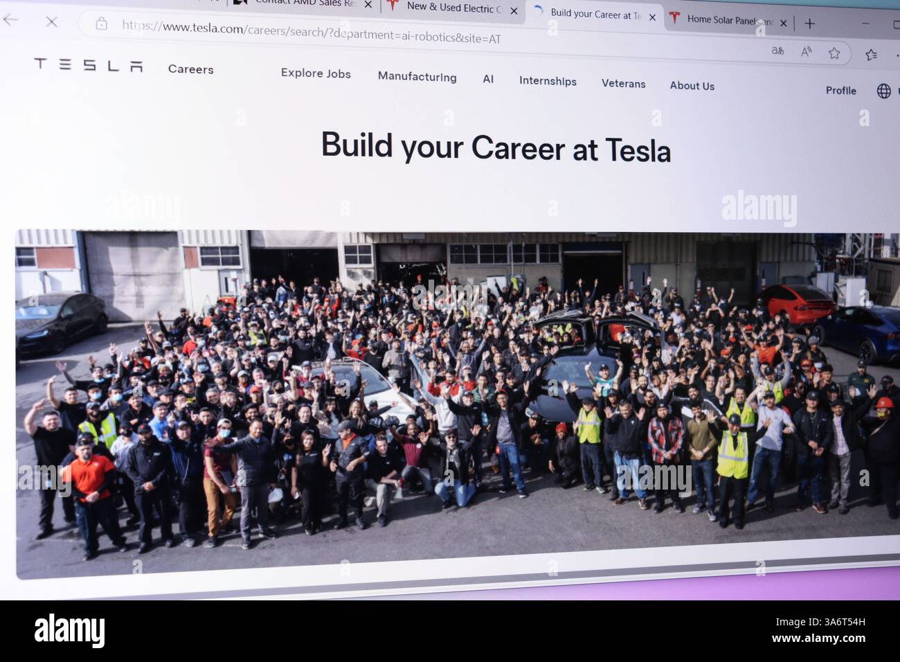 Large group of diverse employees gathered outside tesla facility ...