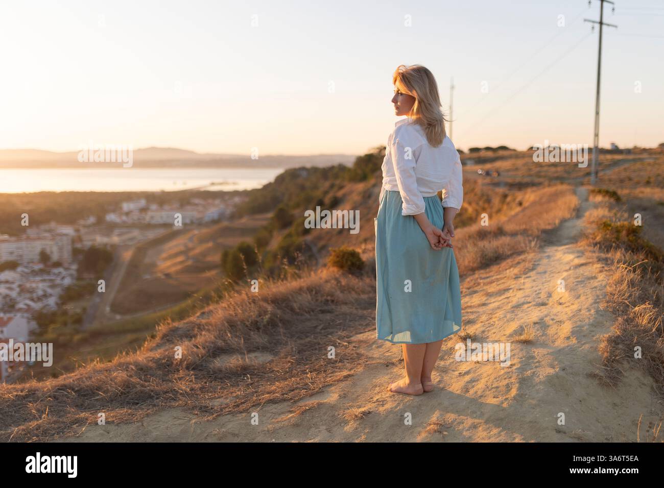 Woman admiring inspiring sunset view over city and sea from hilltop ...