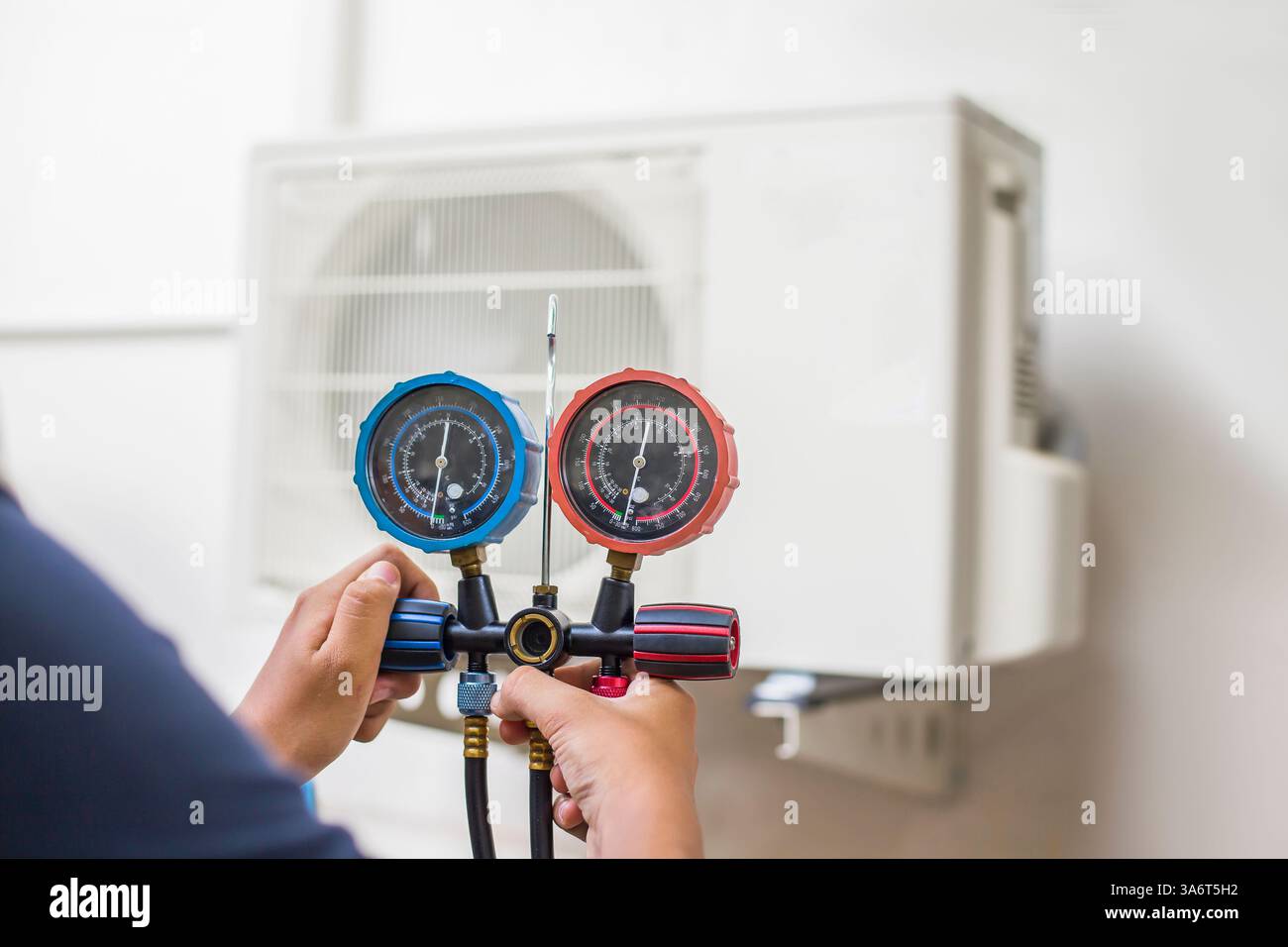 Air repair mechanic using measuring equipment for filling industrial ...