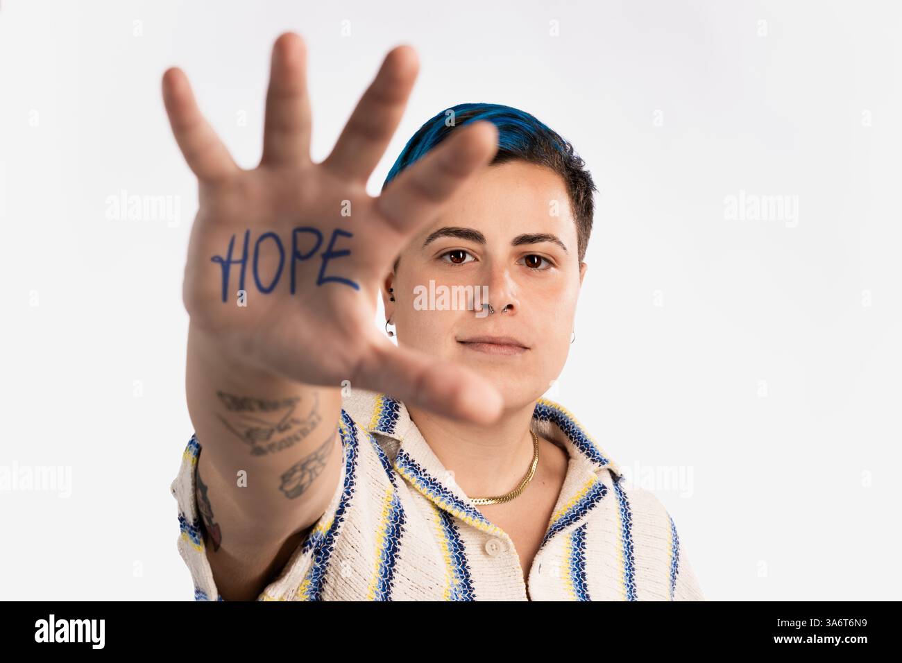 Young woman with bold hairstyle and tattoos showing word hope on hand ...
