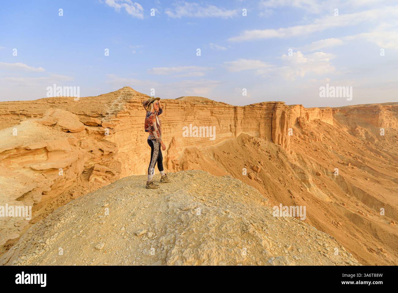 Golden hour illuminating woman tourist at edge of the world escarpment ...