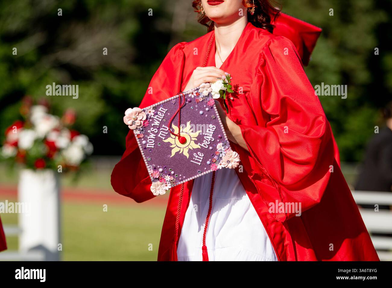 A high school graduate holds her decorated graduation cap during a ...