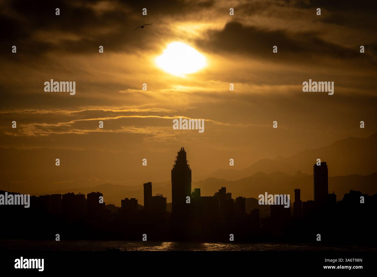 Photo of the sun setting in the evening over the old town of Benidorm ...