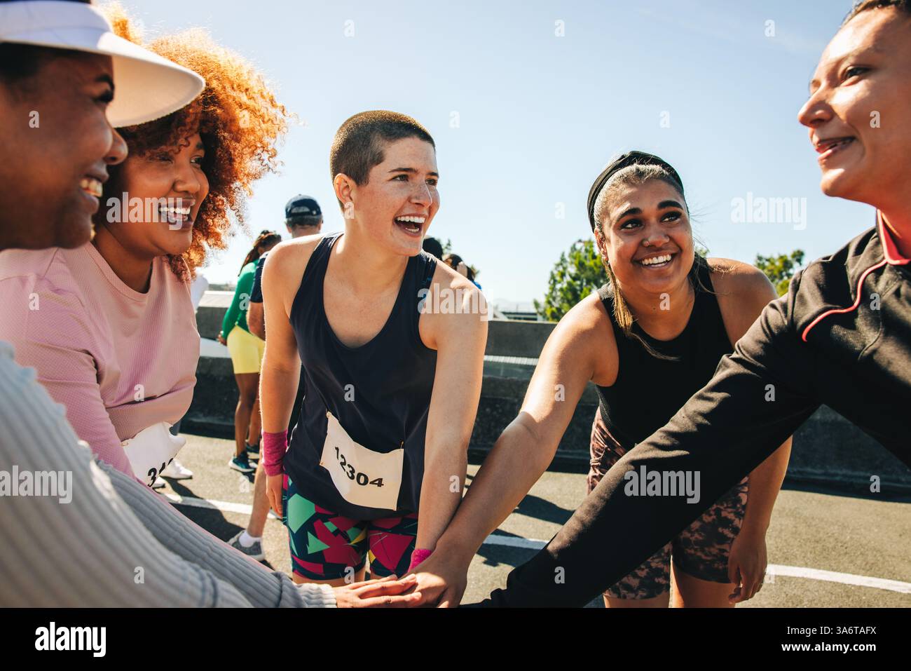 A diverse group of marathon runners gathers in a supportive team huddle ...