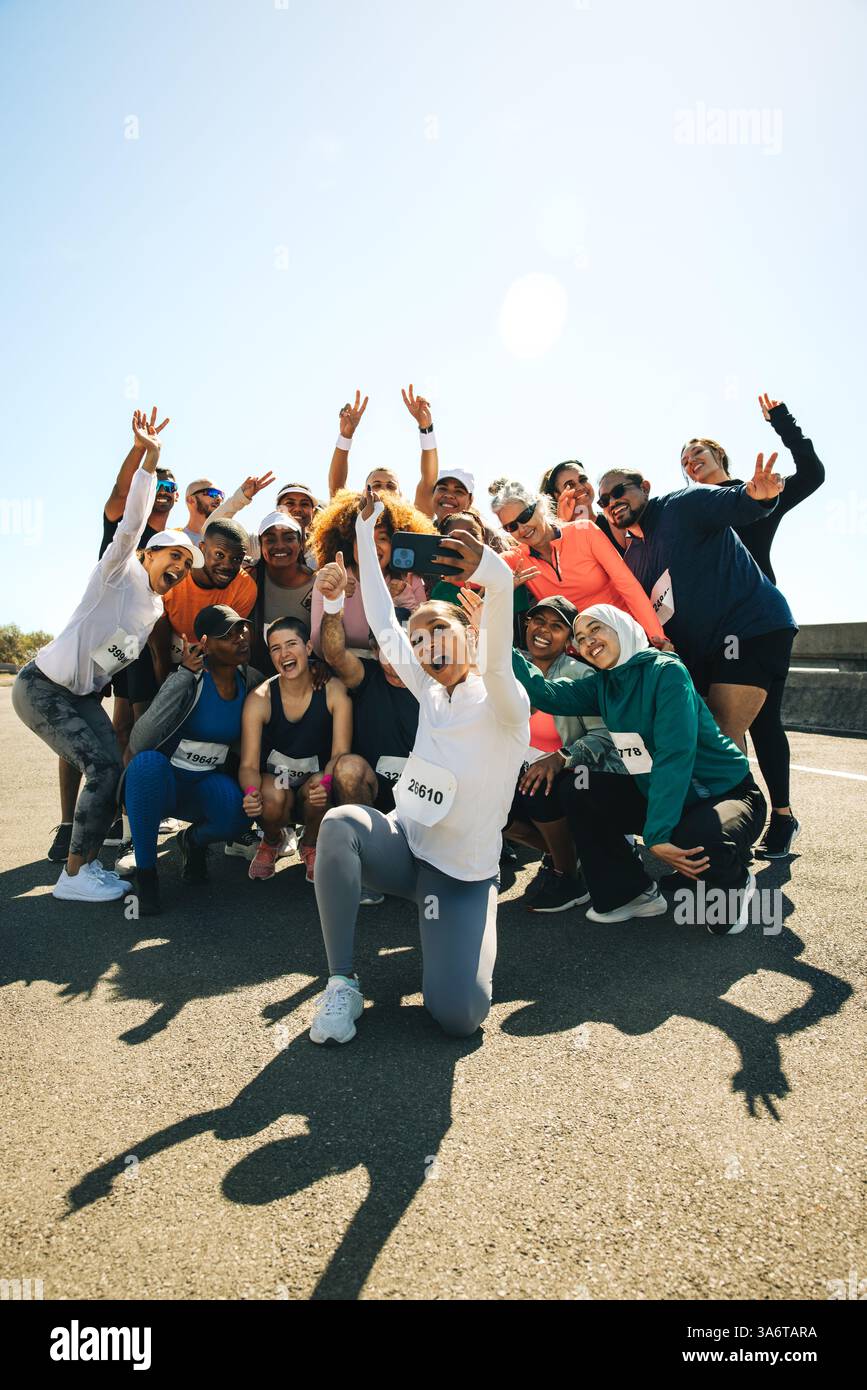 A diverse group of runners enthusiastically gathers to take a selfie ...