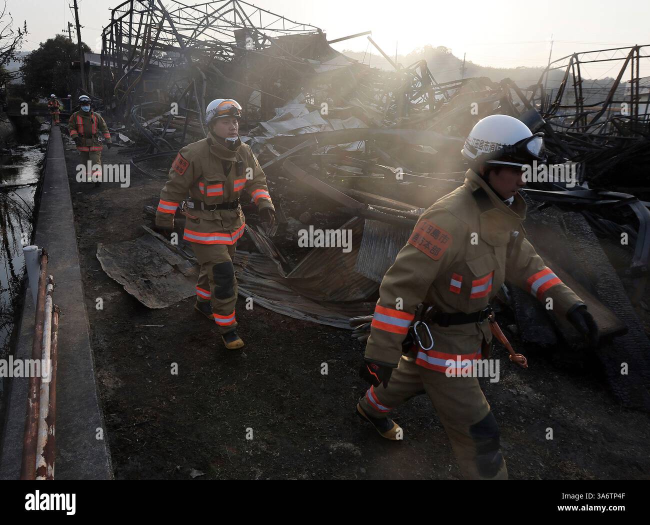 Firefighters work to put out buildings burned down by a forest fire in ...
