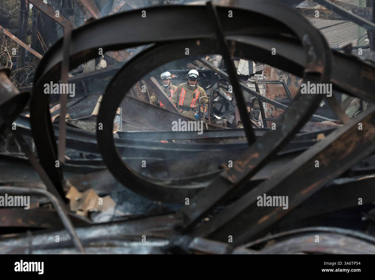 Firefighters work to put out buildings burned down by a forest fire in ...