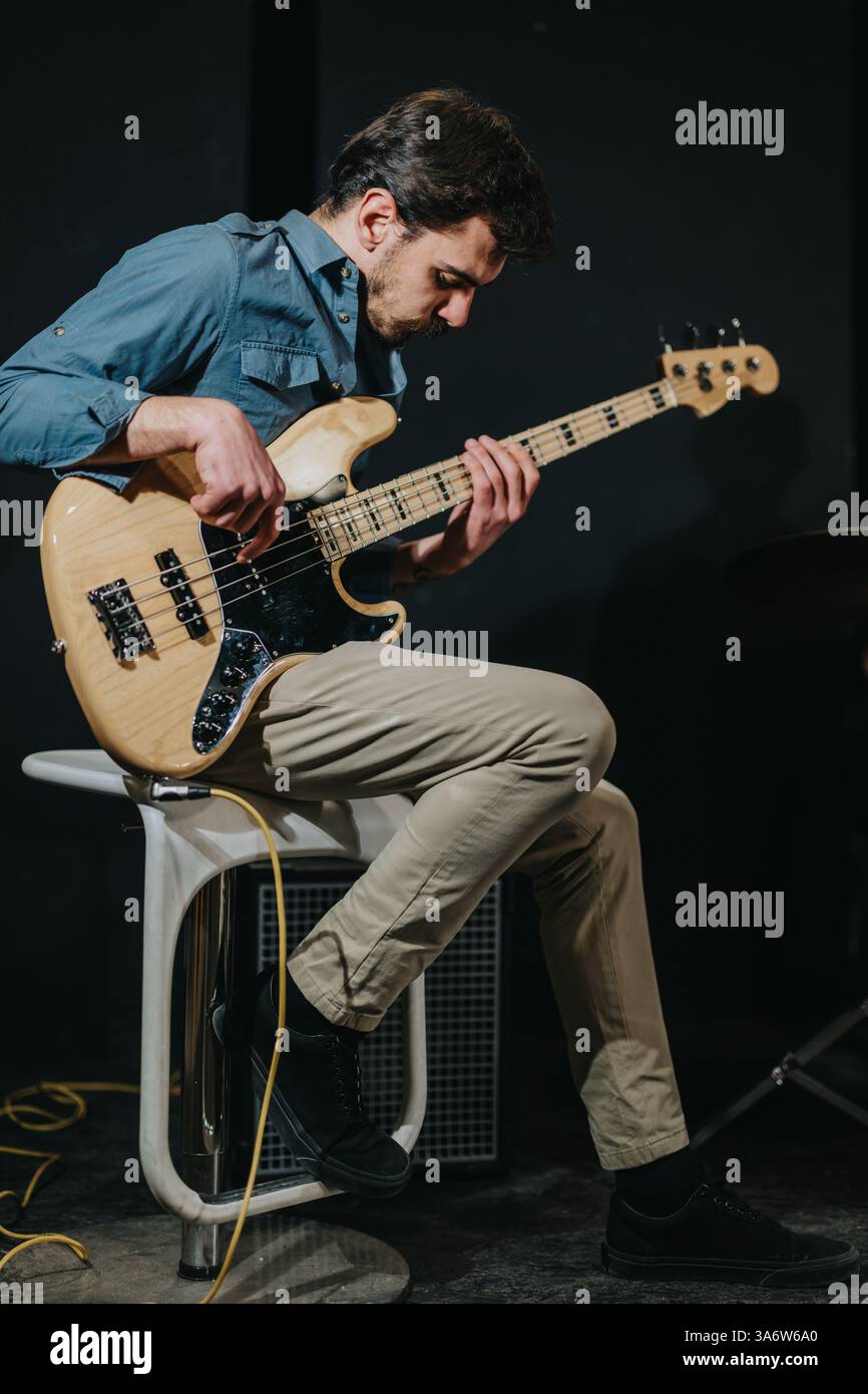 A musician plays a bass guitar while practicing during a rehearsal in a ...
