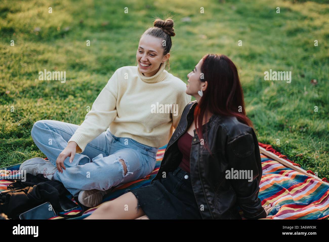 Two women are seated outdoors sharing a serious discussion in a relaxed ...