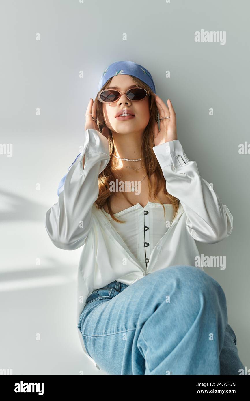 A chic young woman models a trendy spring outfit in a sleek grey studio ...