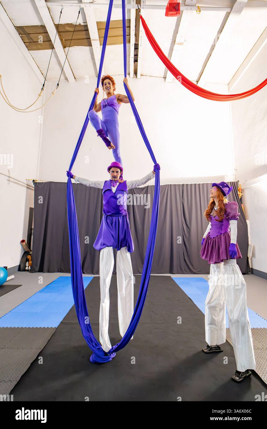 Three circus artists wearing purple costumes performing acrobatics with ...