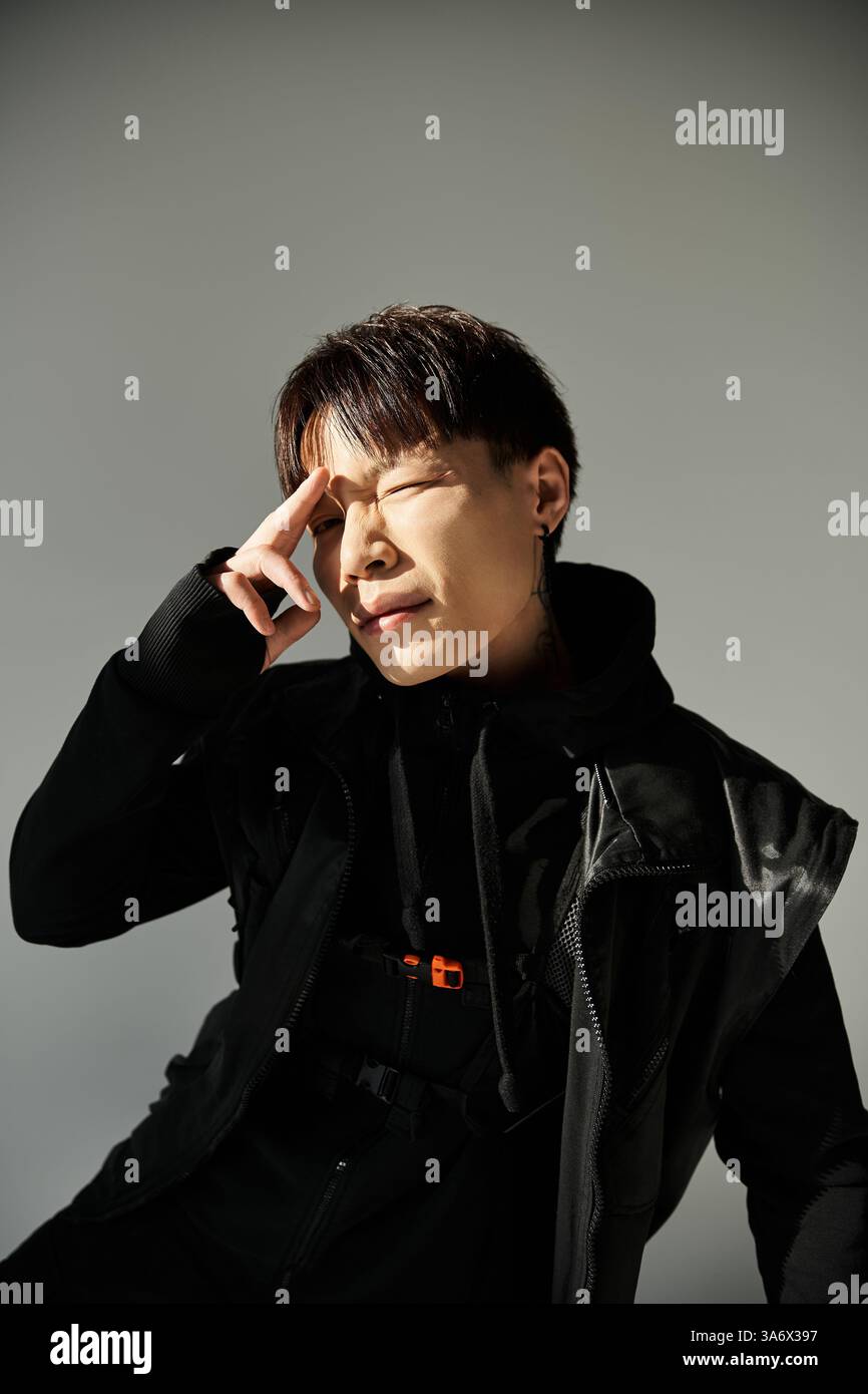 A handsome young Asian man showcases his stylish outfit, playfully ...