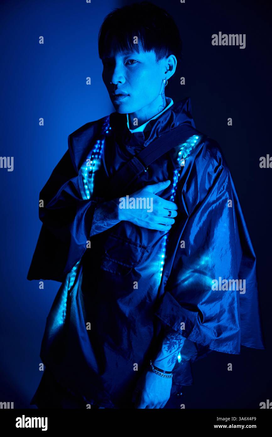 Handsome young asian man poses confidently in striking blue light ...