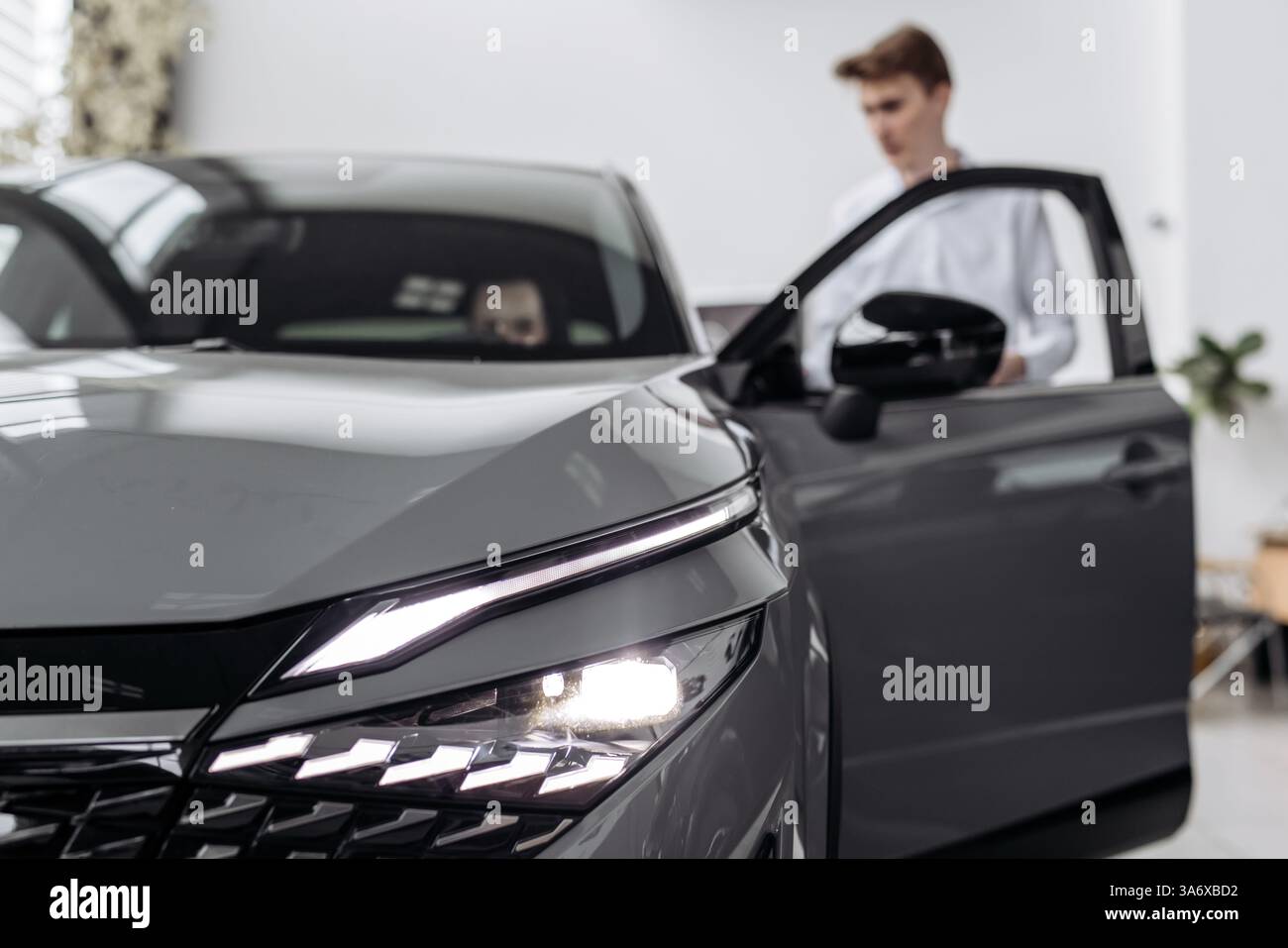 A car sales manager shows a vehicle to a customer in a luxurious ...