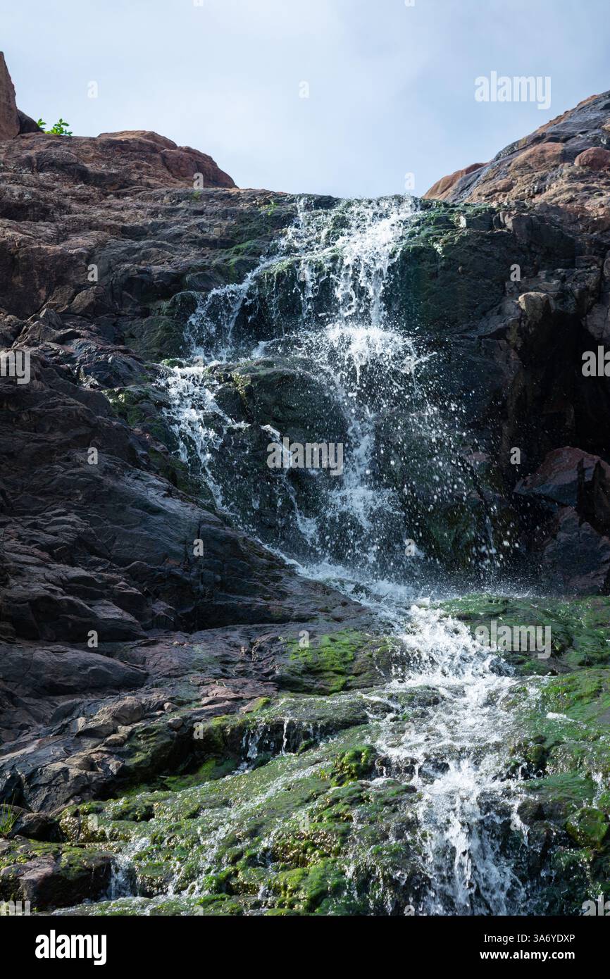 Small waterfall, falling of water behind the rock Stock Photo - Alamy