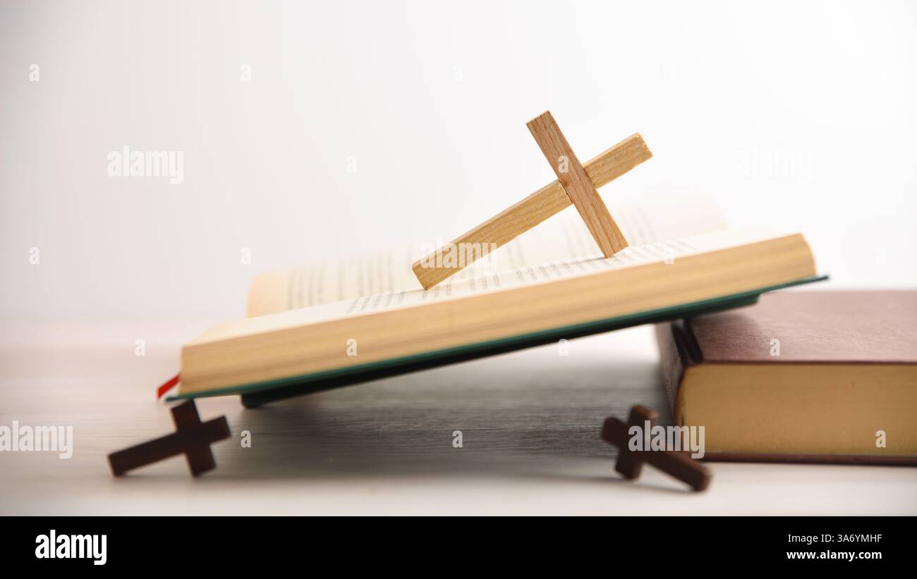 Open Bible on a wooden table with several wooden crosses and isolated ...