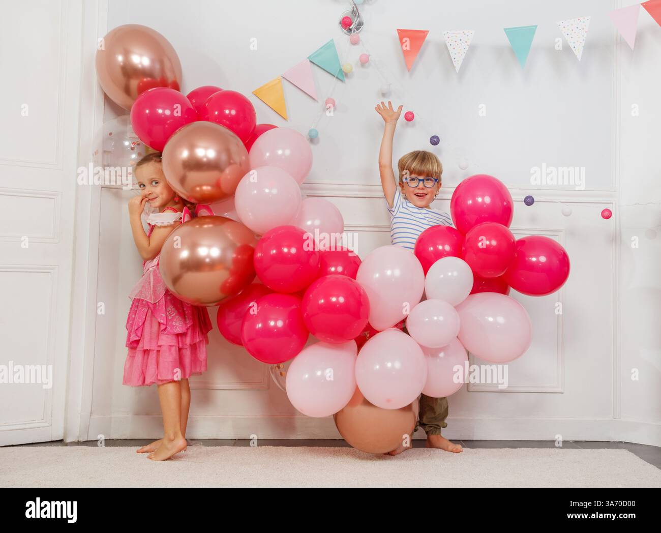 Two kids boy, girl, hiding in vibrant balloons at birthday party Stock ...