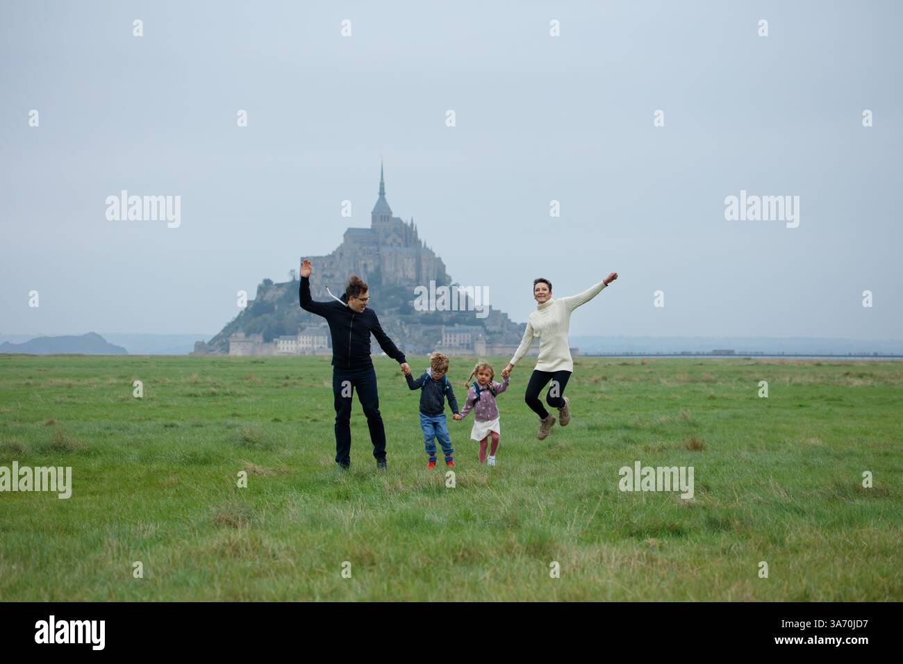 Happy family jumping in front of Mont Saint-Michel on cloudy day Stock ...