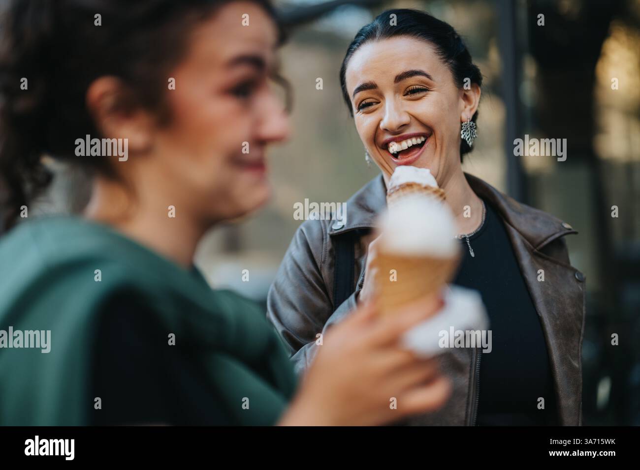 Two women enjoying ice cream cones and sharing a moment of laughter ...