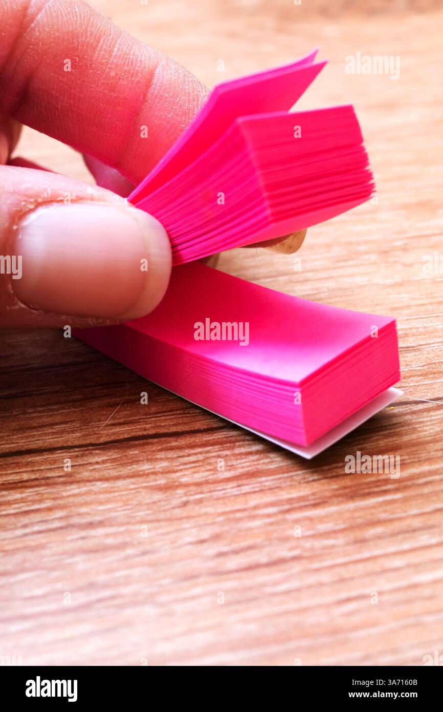 An individual is holding a sizable stack of colorful pink sticky notes ...