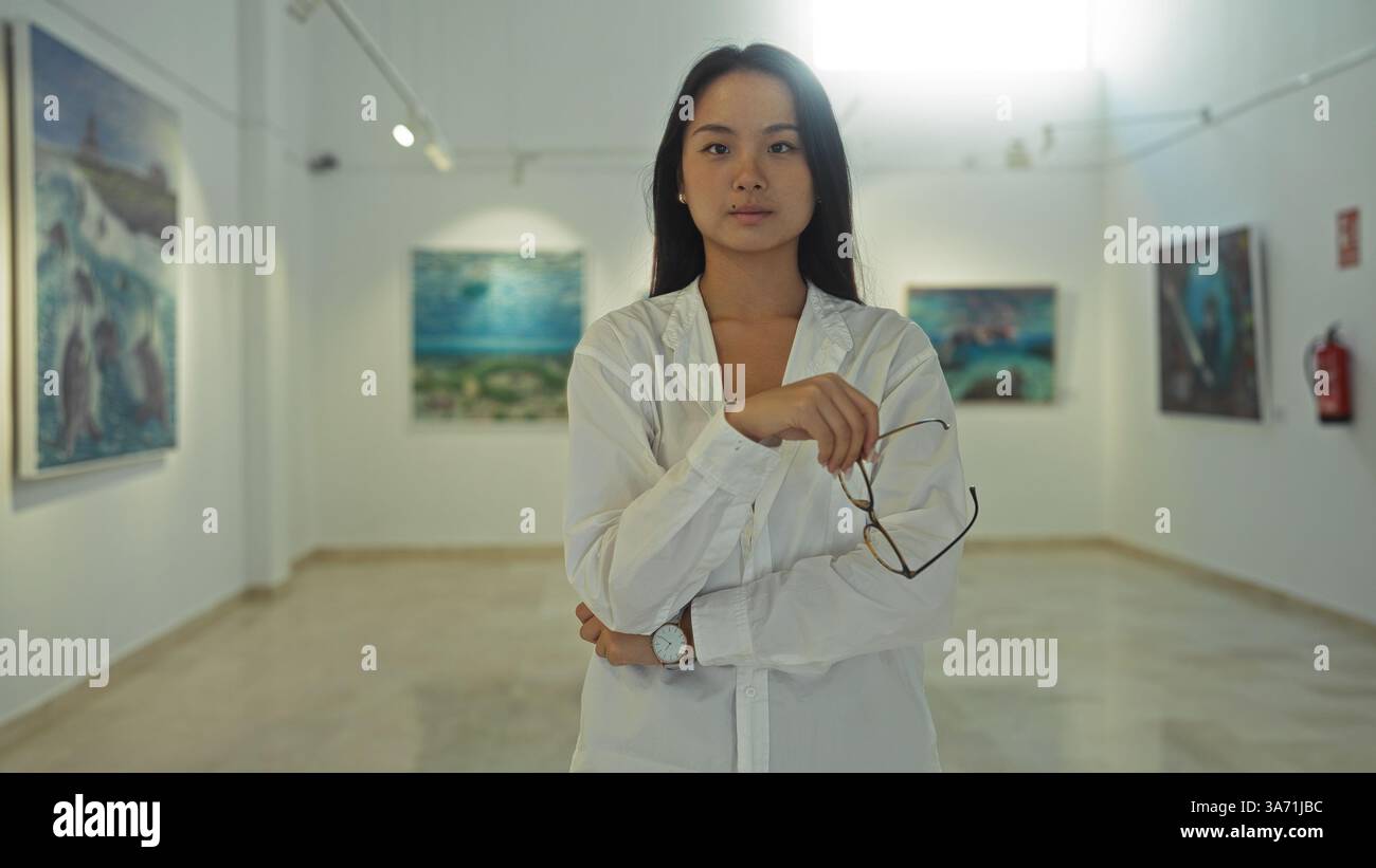 Young chinese woman in white shirt standing in an art gallery room ...