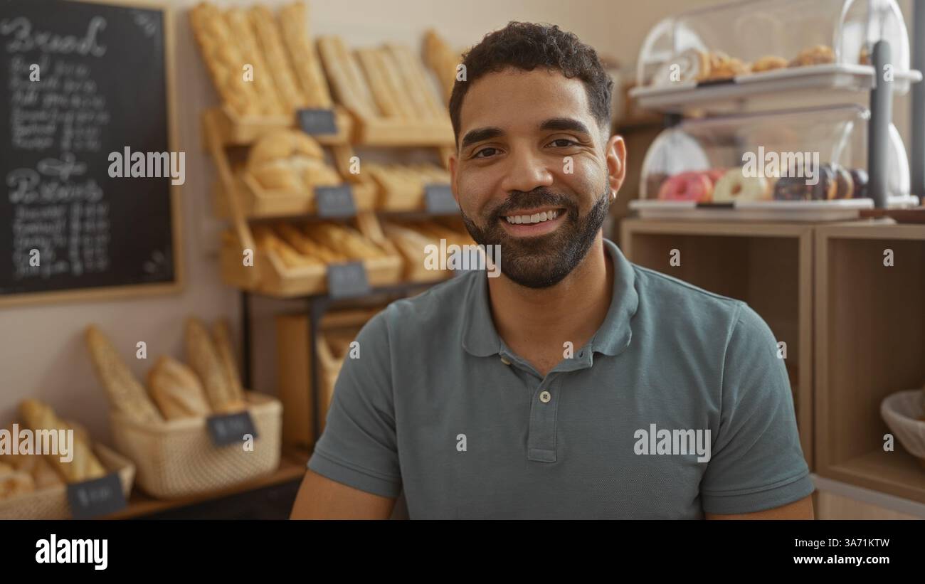 Young man smiling in bakery with shelves of bread and pastries in ...