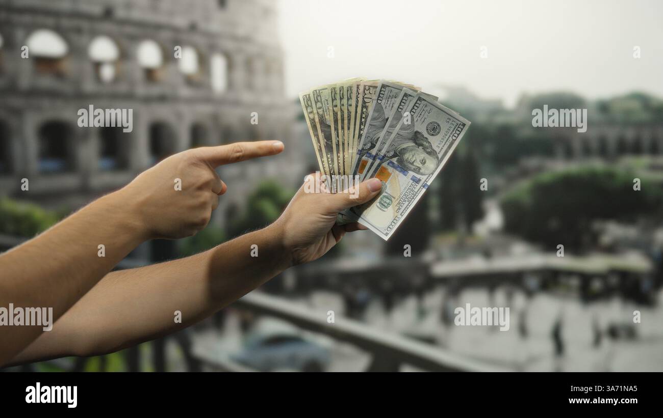Hand of man points at american dollars held near the roman coliseum ...