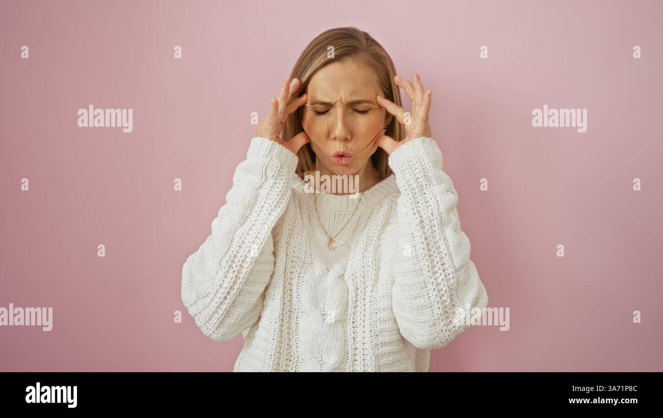 Woman looking stressed against a pink background, touching her temples ...