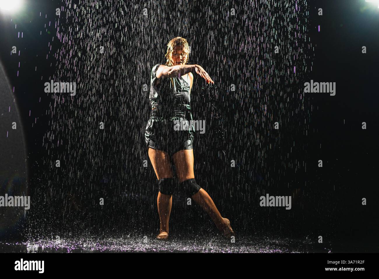 Contemporary woman dancer posing in rain water on black background ...