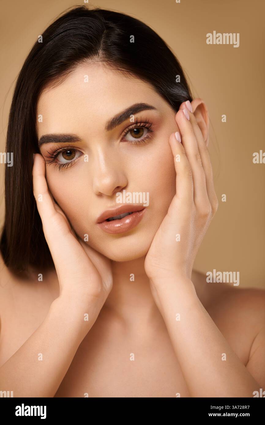 Young woman showcases radiant, healthy skin while posing gracefully in a well-lit studio Stock ...