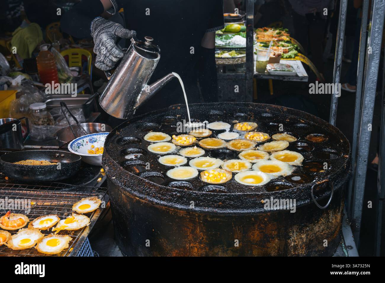 cooking a traditional Vietnamese dish Banh Khot with shrimps and corn ...