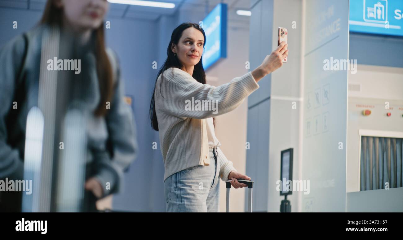 Crowded International Airport Terminal: Beautiful Woman Takes Selfie on Smartphone, Waits for ...
