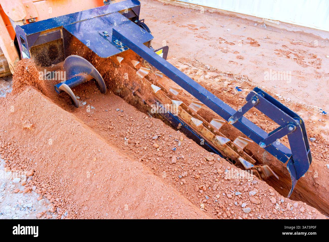 Trencher machinery is actively digging into earth at construction site ...