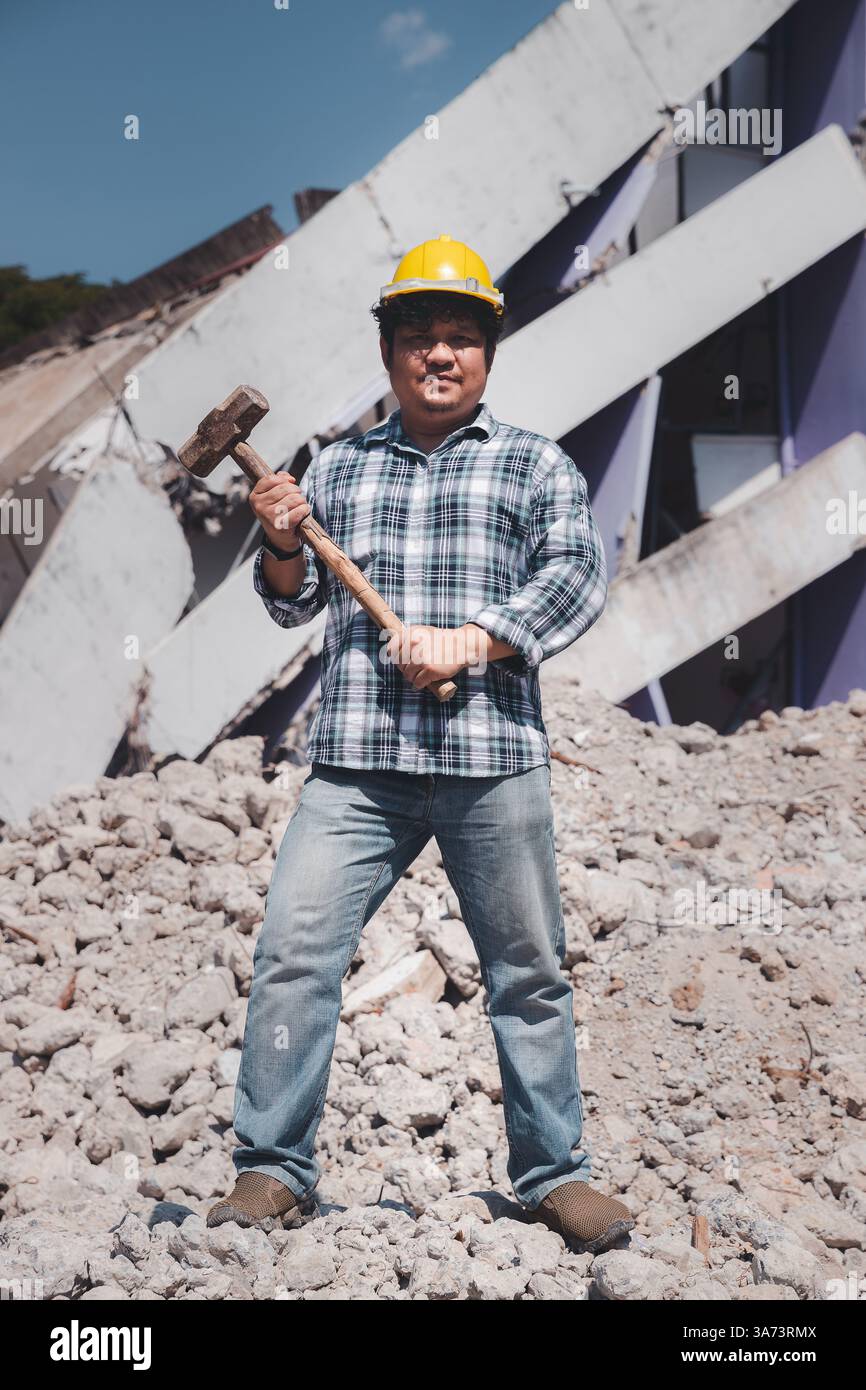 Construction worker holding a sledge hammer standing on demolish ...