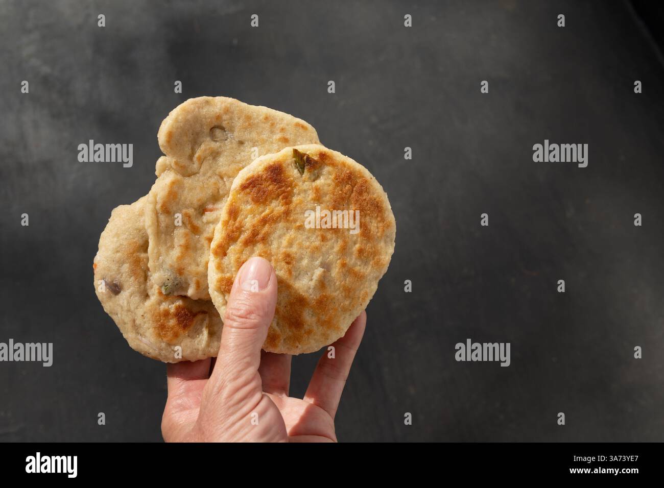 Authentic Sri Lankan three Pol Coconut Roti in hand against gray wall ...
