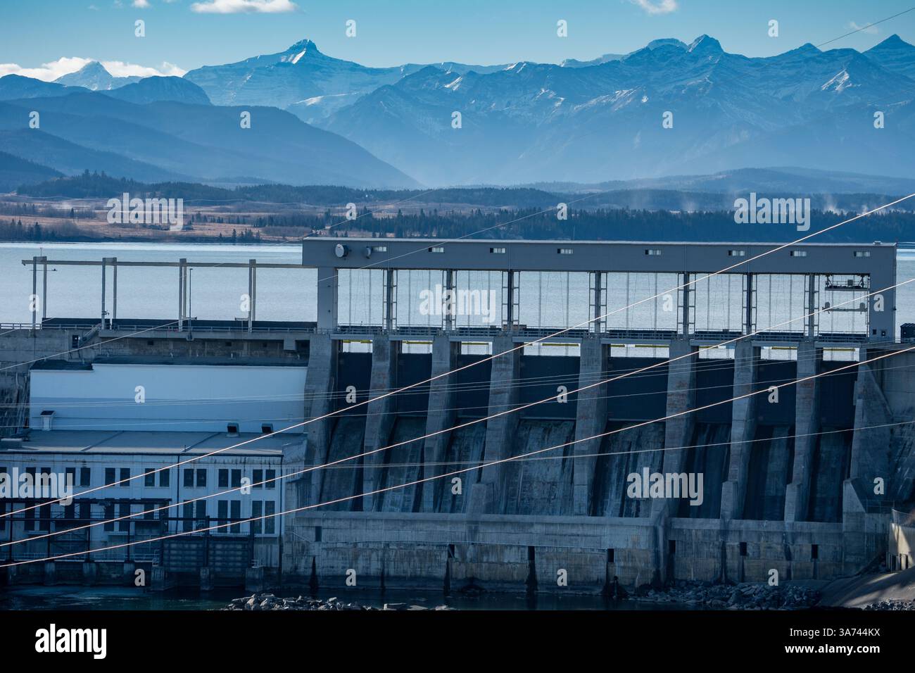 Hydro dam with power station overlooking distant Canadian Rockies near ...