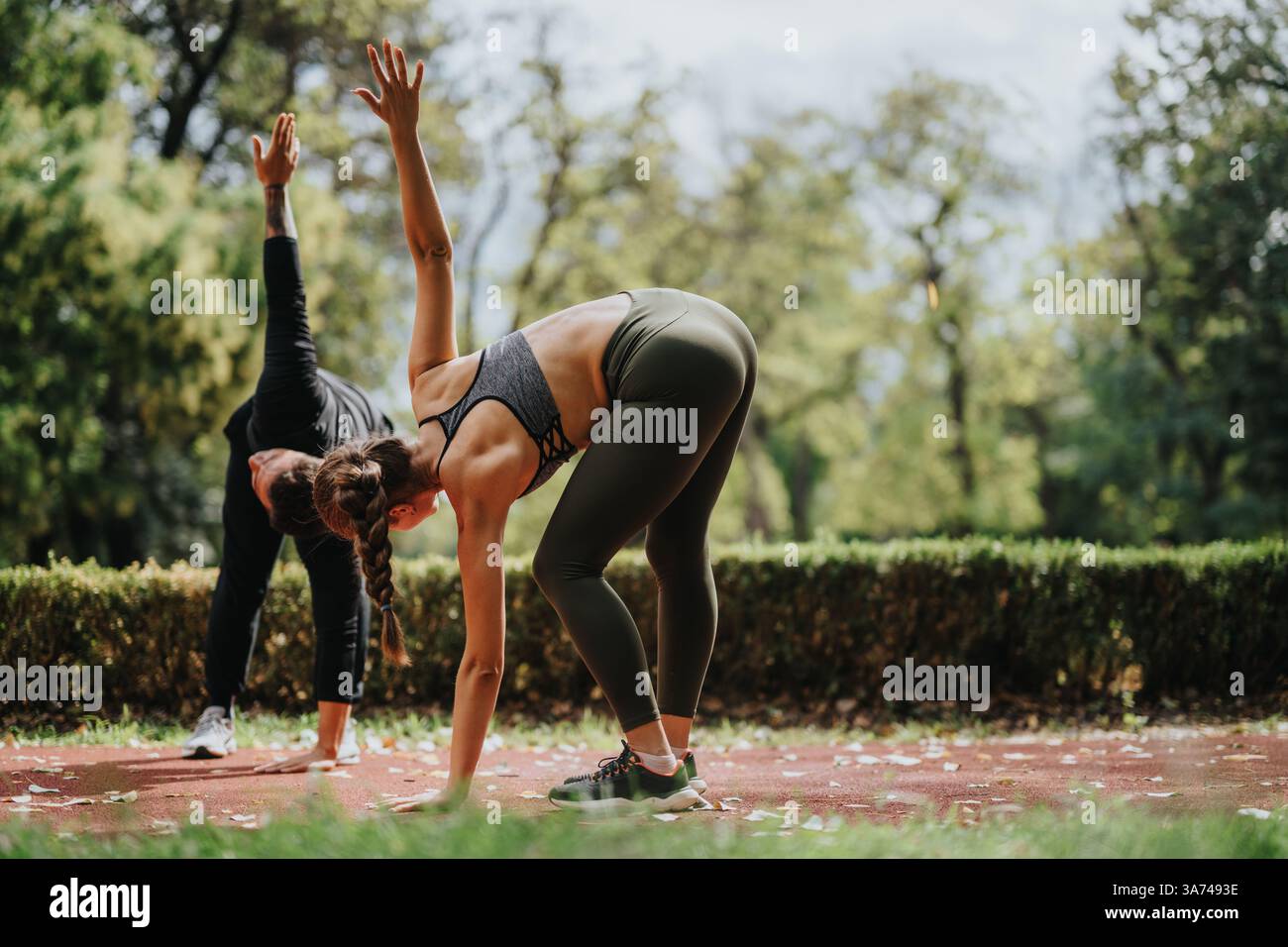 Two friends engage in an outdoor fitness session, performing dynamic ...